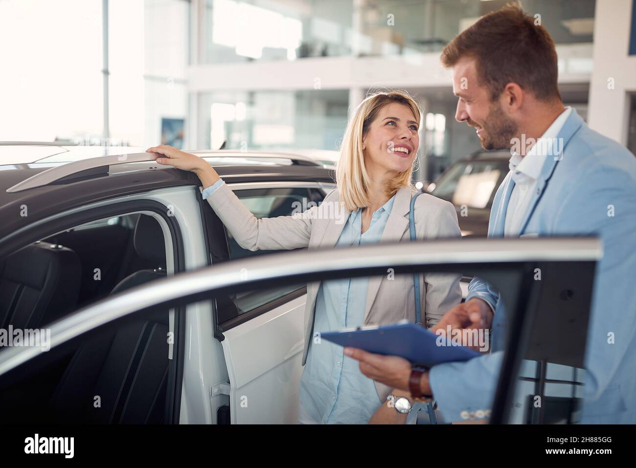 Smiling female in car showroom with car seller buying new car Stock ...