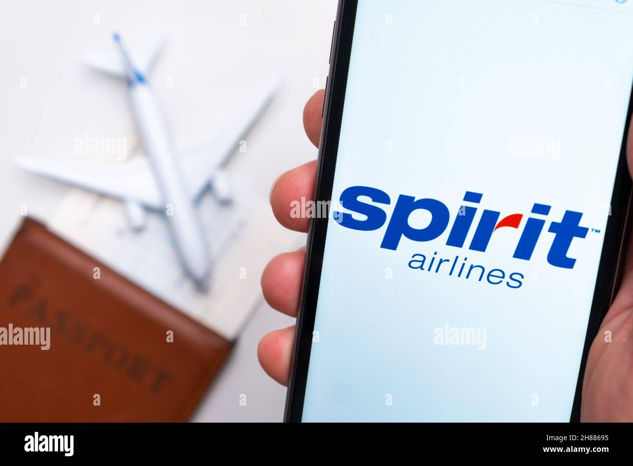 Spirit Airlines app on the cell phone screen in mans hand with plane ...