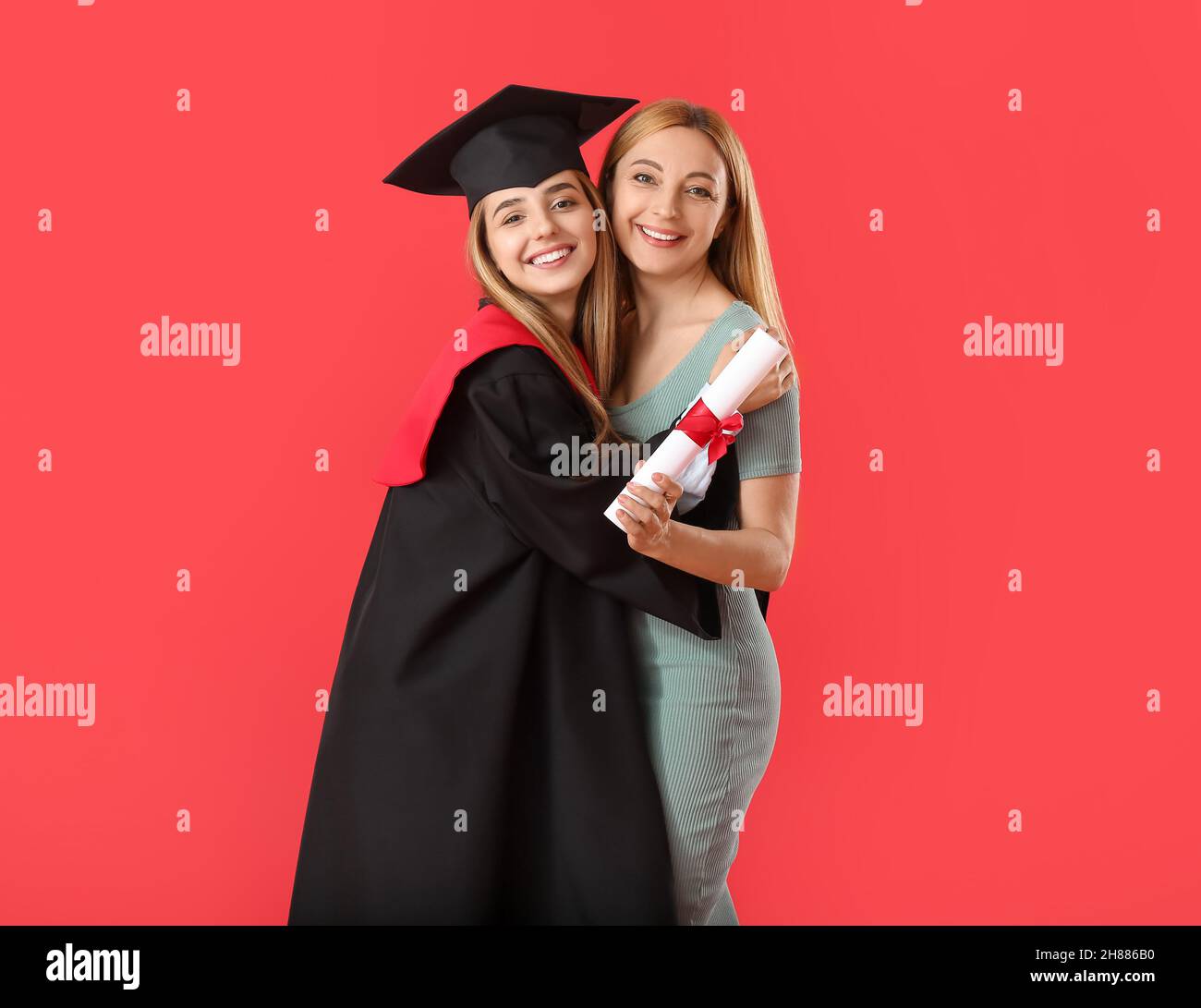Happy female graduation student with her mother on color background ...