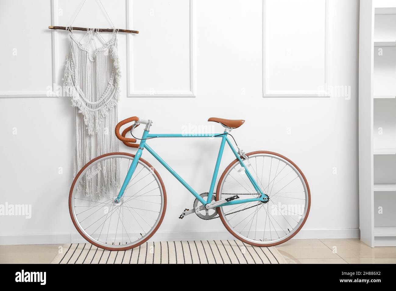 Modern bicycle and decor hanging on white wall Stock Photo - Alamy