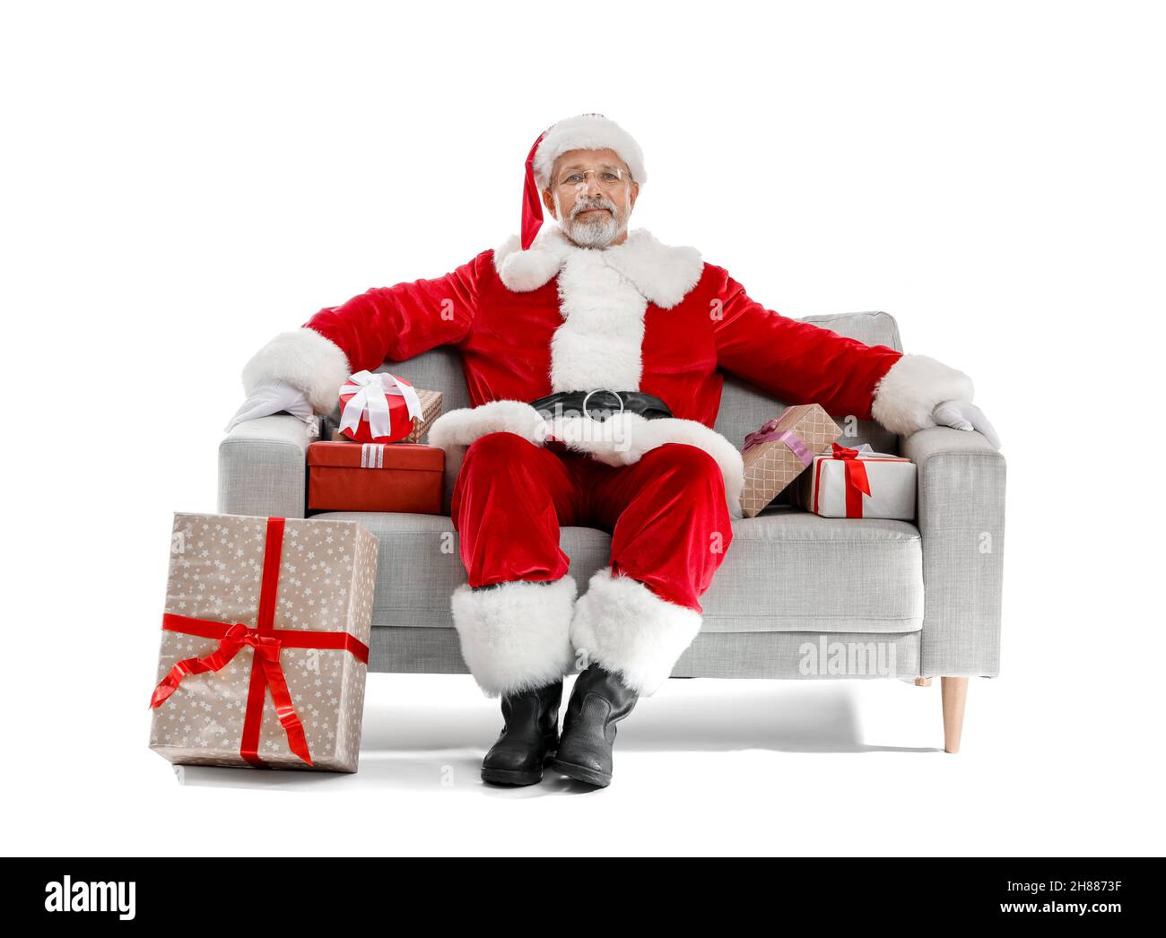 Santa Claus sitting on sofa with Christmas presents against white ...