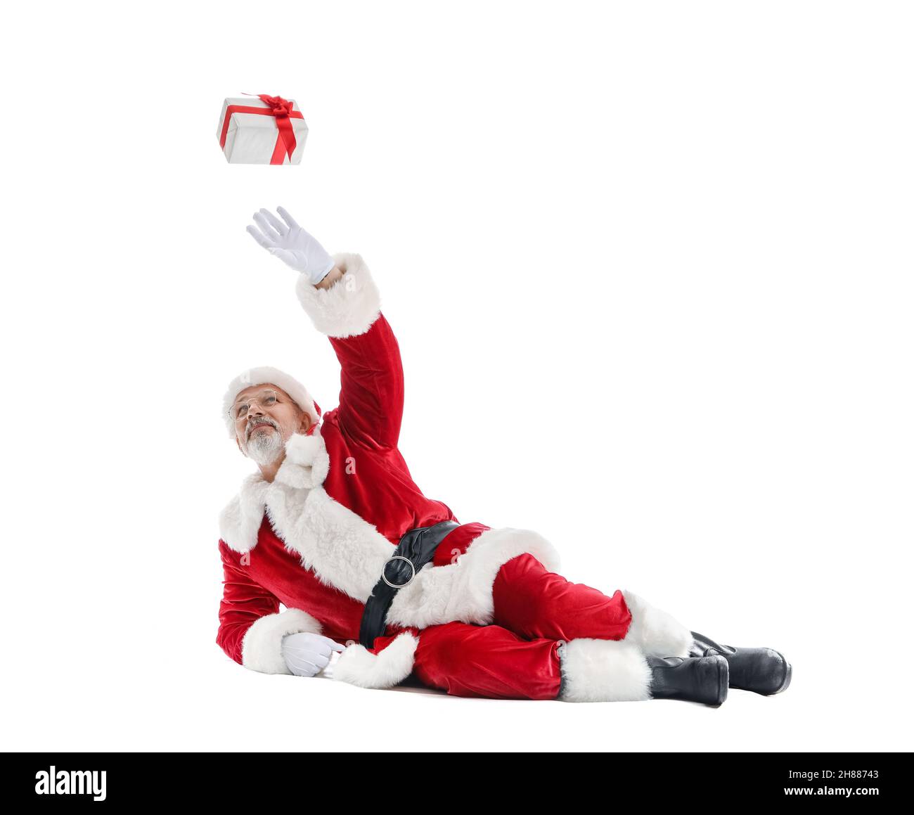 Santa Claus lying and catching gift box on white background Stock Photo ...
