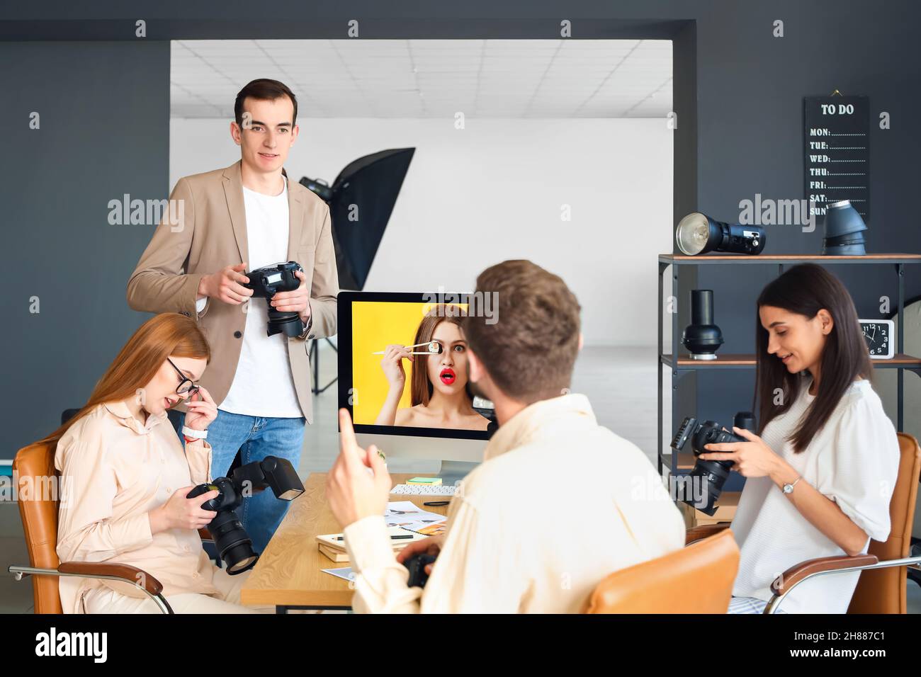 Professional photographer teaching young people in studio Stock Photo ...