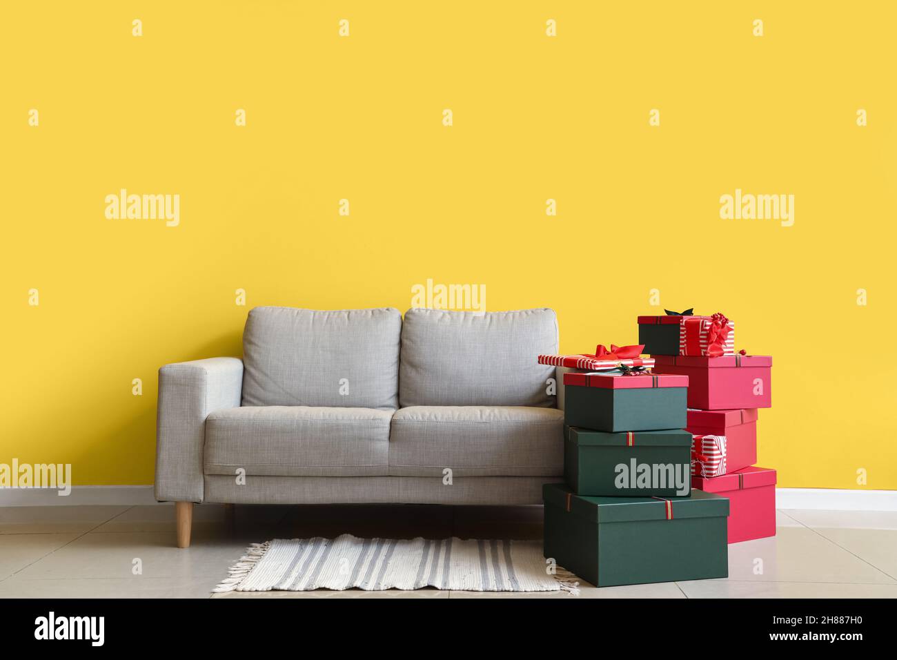 Stack of different Christmas gift boxes on floor near sofa in room ...