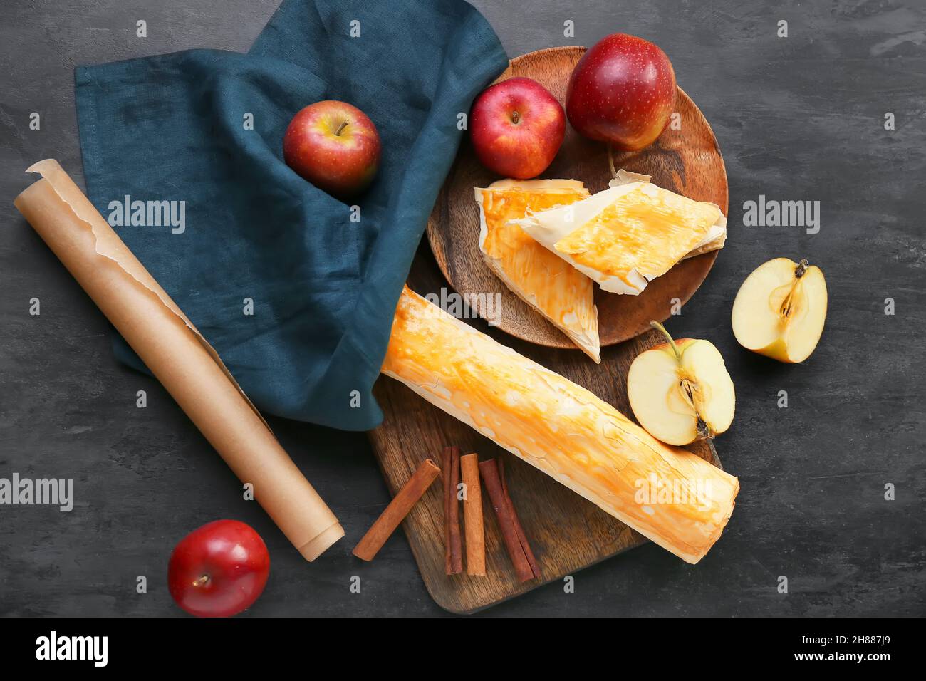 Wooden board with tasty apple strudel and fresh fruits on black ...