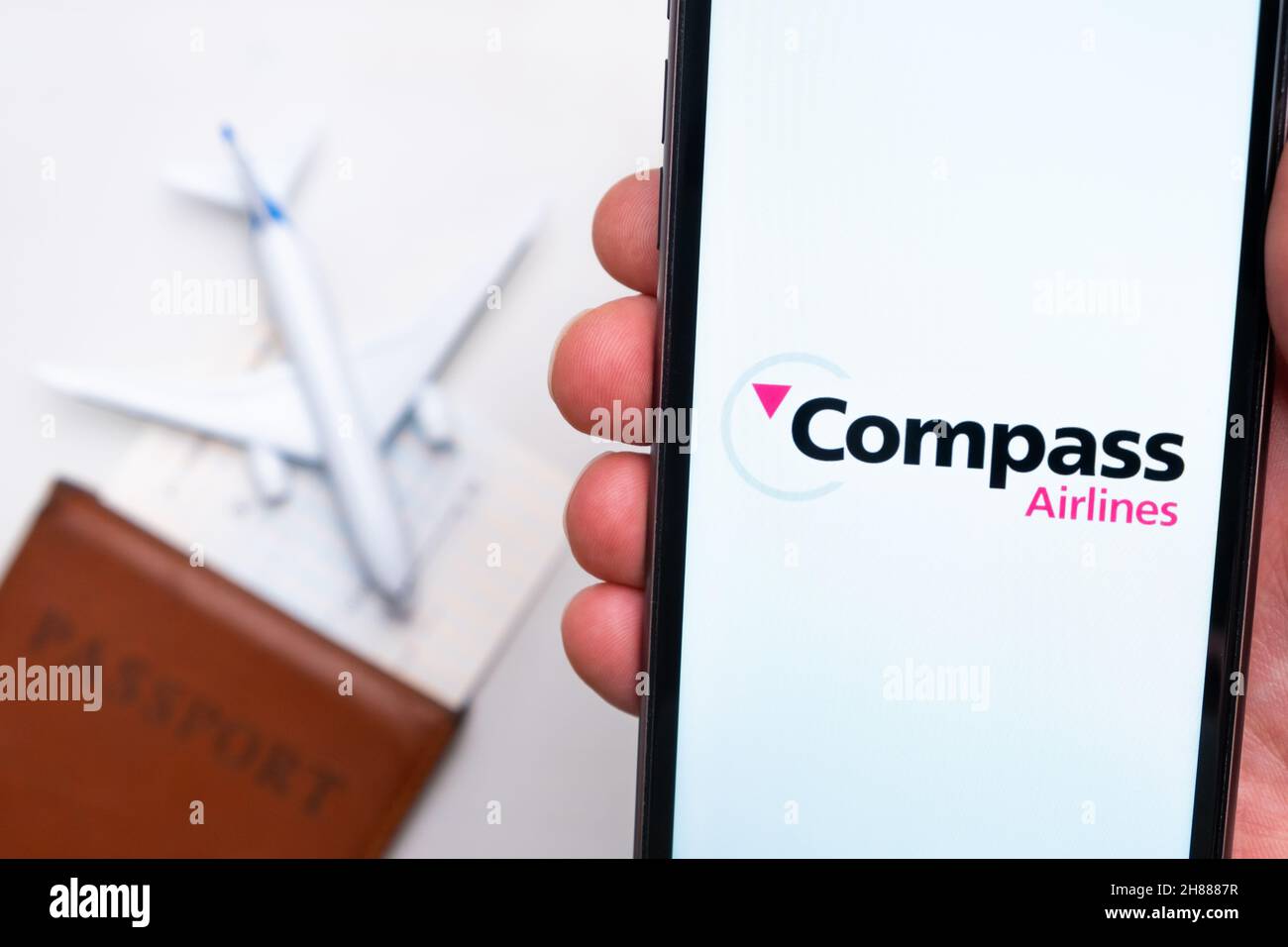 Compass Airlines app logo on the screen of mobile phone. A blurry image ...