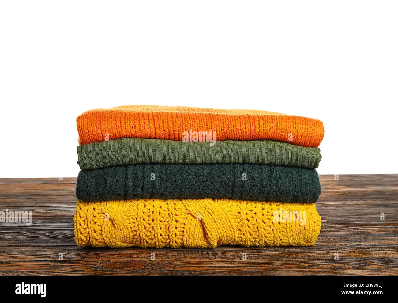 Trendy warm sweaters on wooden table against white background Stock ...