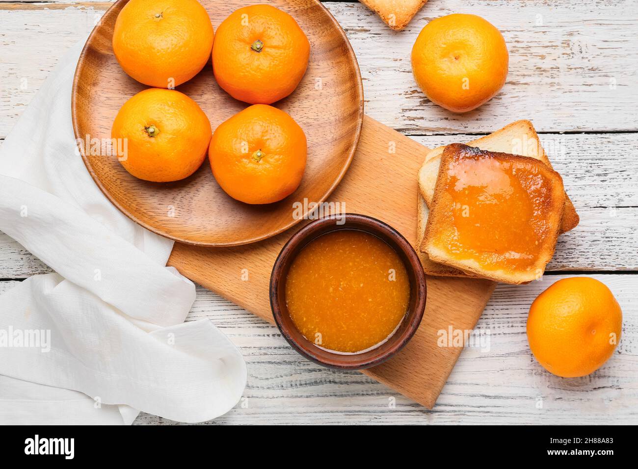 Bowl of tasty tangerine jam and bread on light wooden background Stock ...