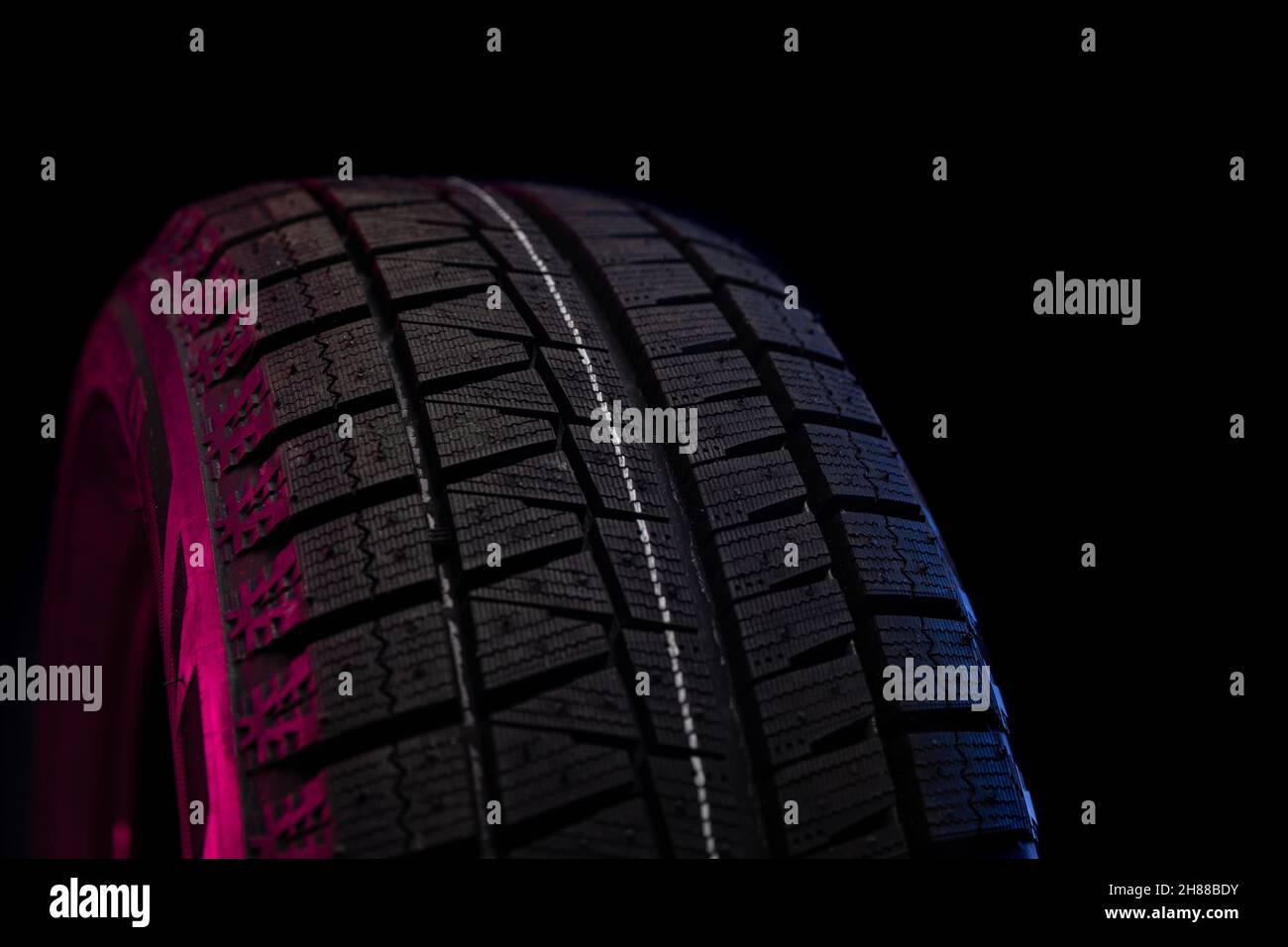 close-up of a tire tread on a black background with red-blue ...