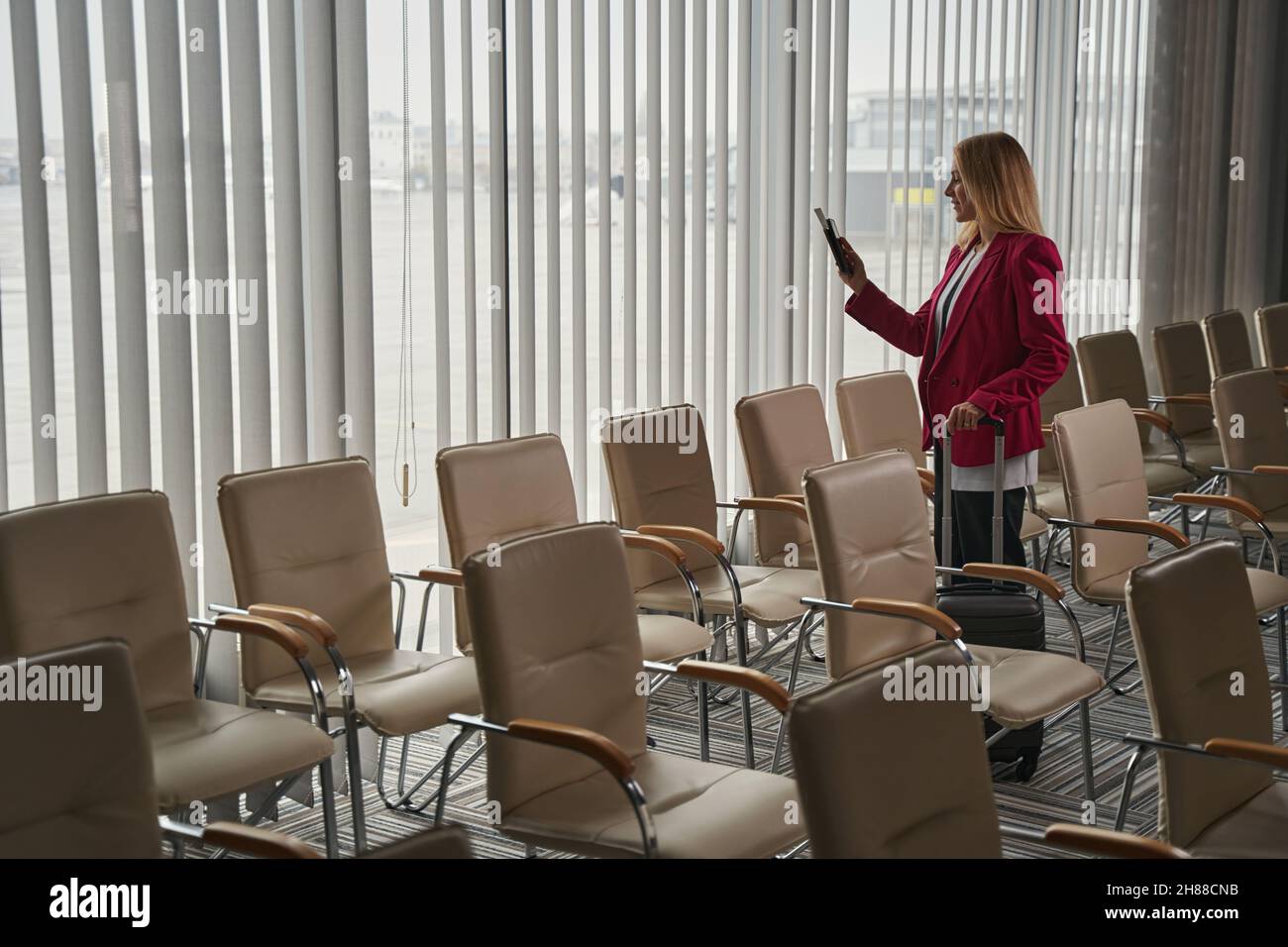Woman with smartphone staring at its screen in waiting hall Stock Photo ...