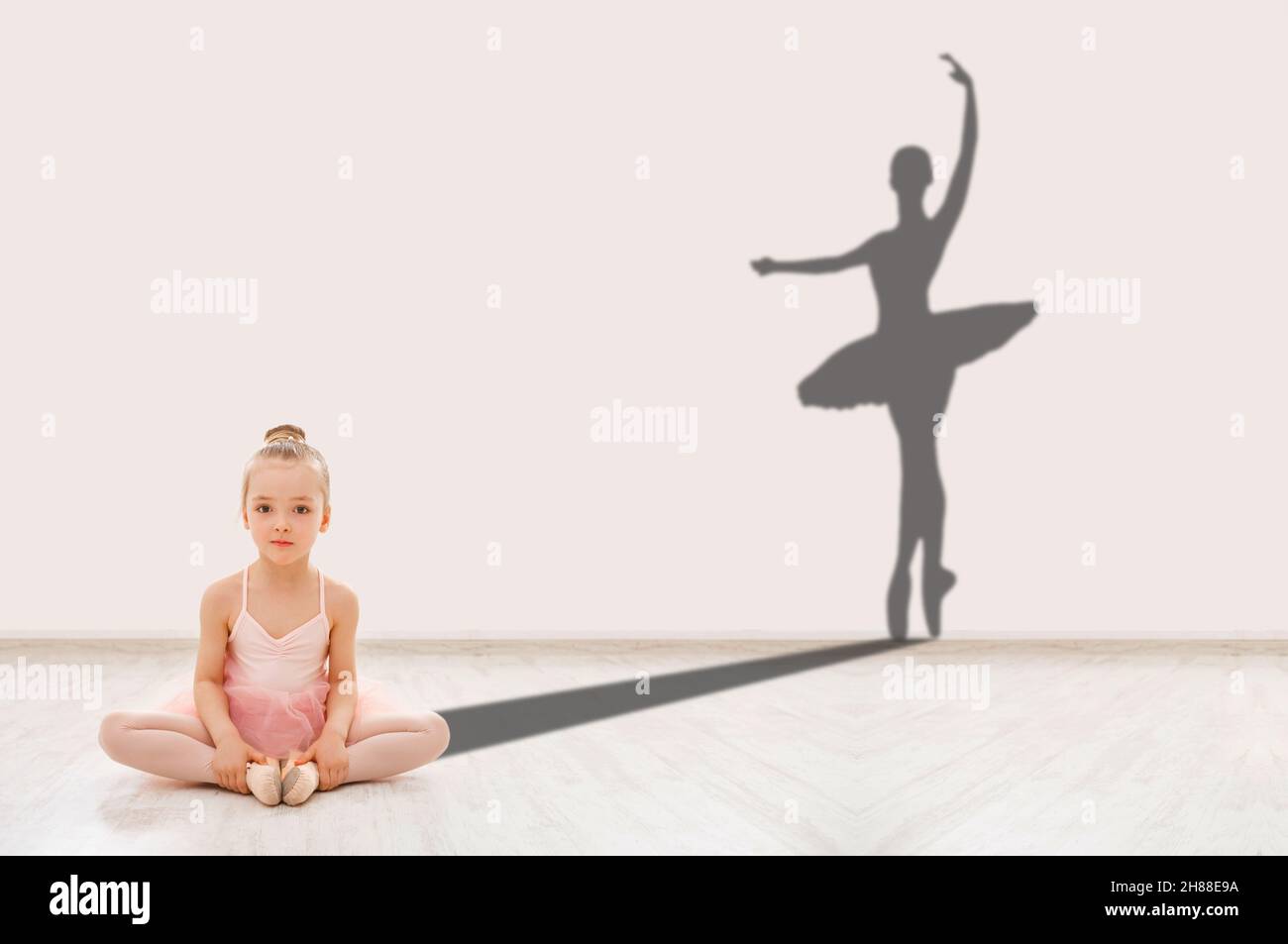 Little ballerina on floor and shape of adult dancer behind Stock Photo ...