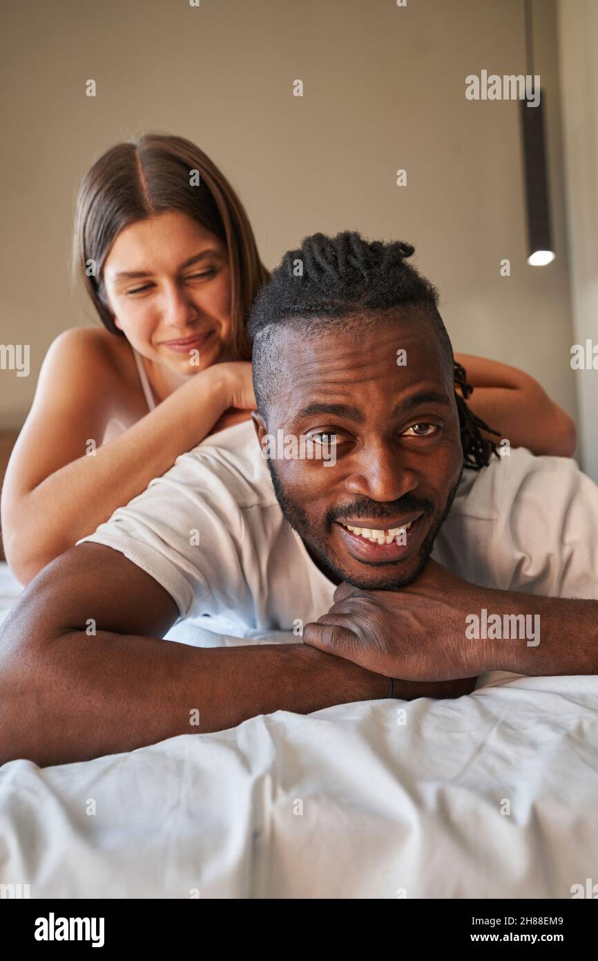 Happy romantic mixed-race couple lying in bed Stock Photo - Alamy