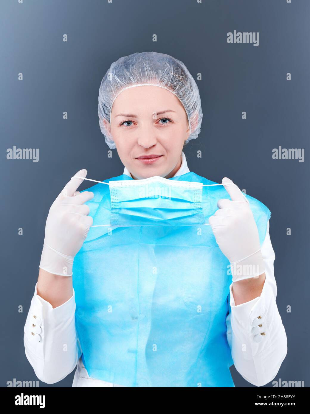 young nurse in a medical mask poses in front of the camera on a medical ...