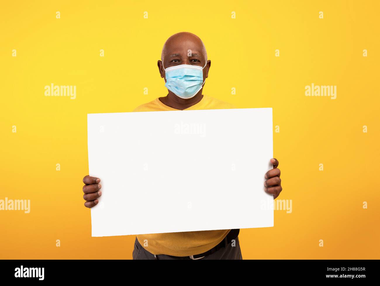 Senior black man wearing anti covid face mask, showing empty ...