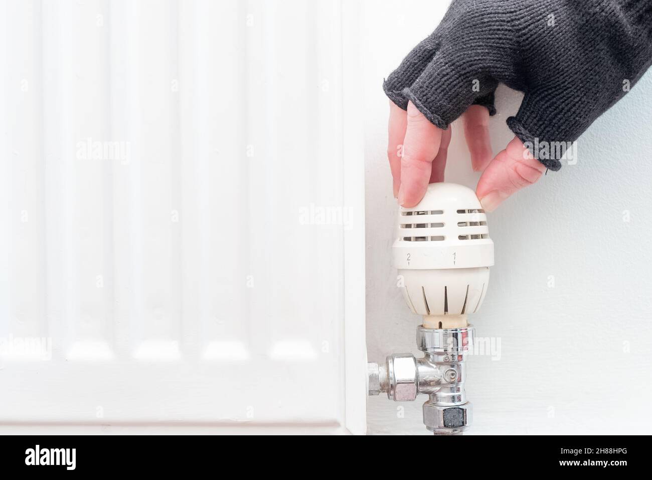 Hand and Glove turning radiator valve for heating Stock Photo - Alamy