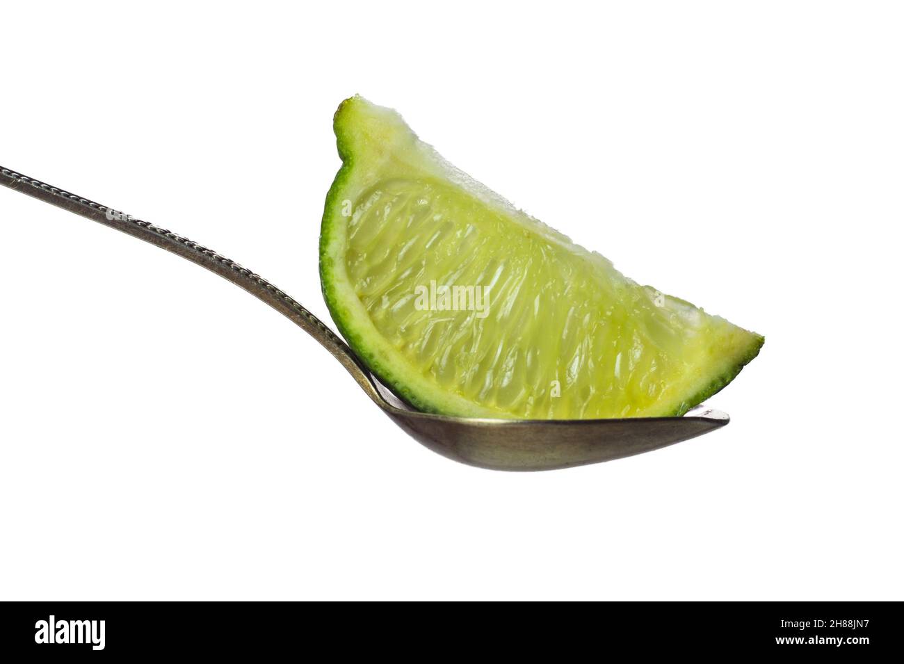 Slice of green lime in spoon isolated on white Stock Photo - Alamy