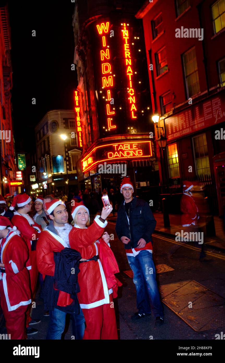 Christmas revellers in Santa costumes queuing to get in to a club ...