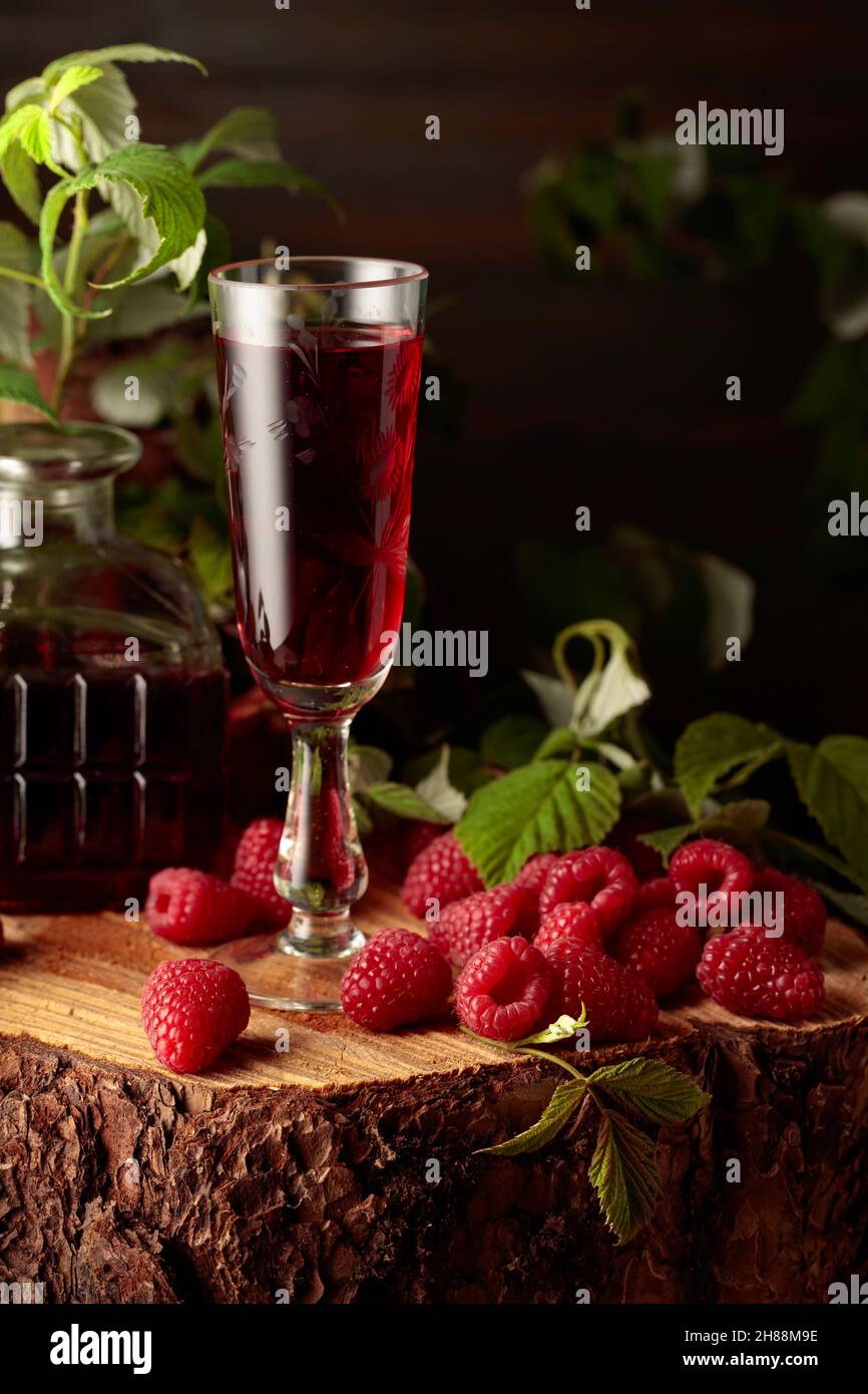 Raspberry liquor and fresh berries with leaves on a pine stump Stock ...
