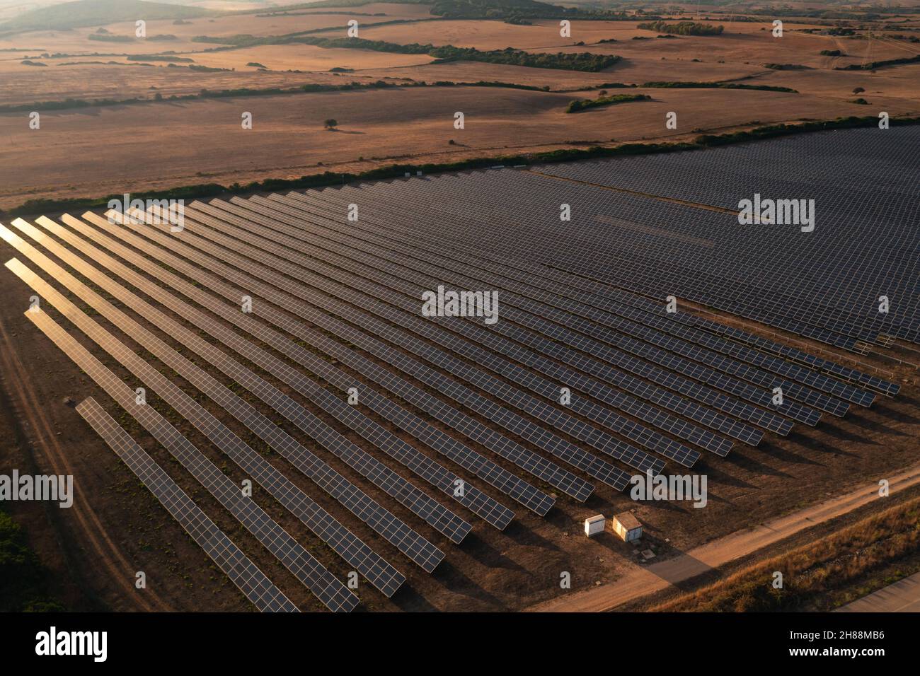 Aerial shot of ground-mounted solar panels, on a solar farm, at sunset ...