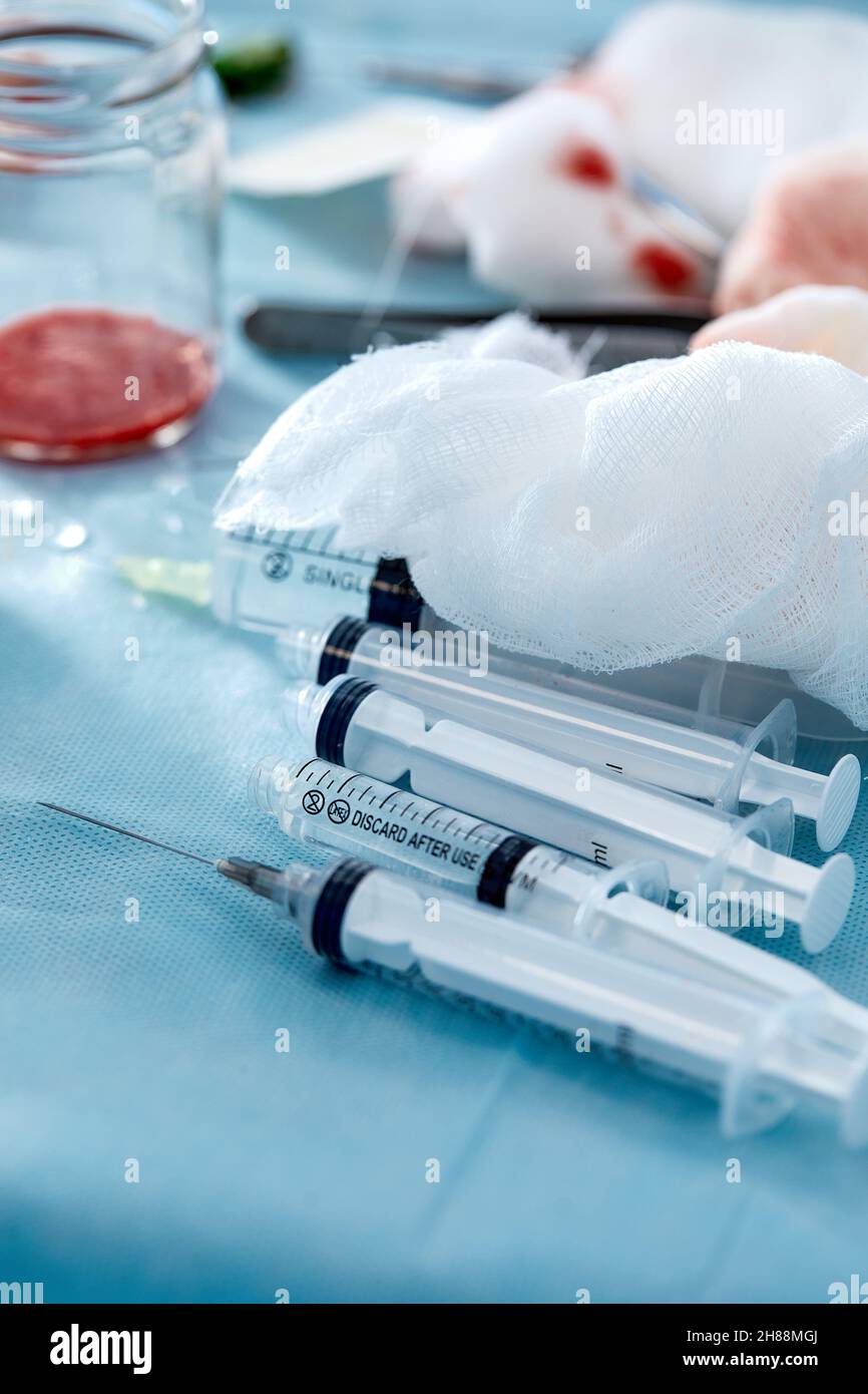 Many syringes on a blue sheet in operation room. Different sizes of ...