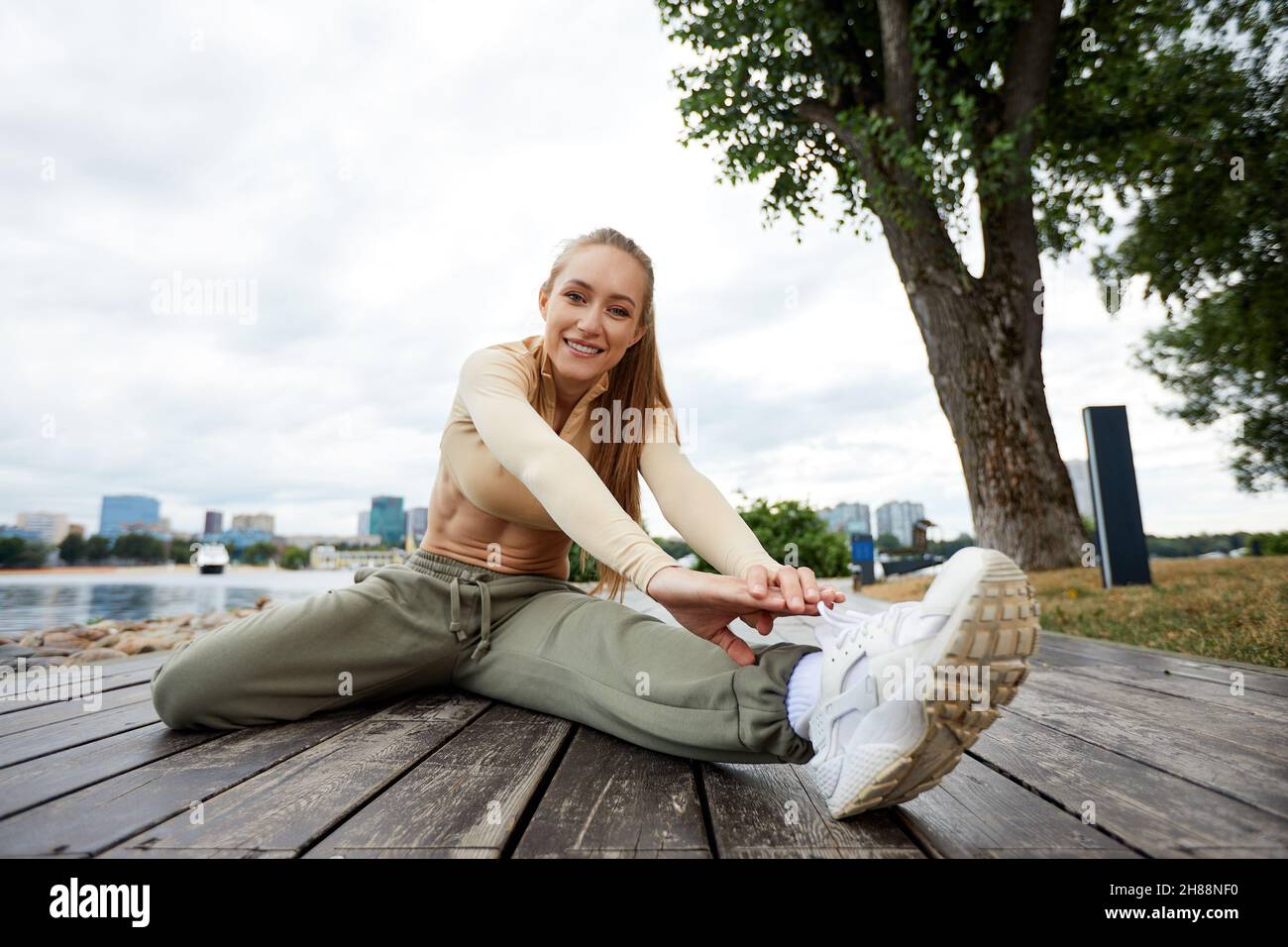 Blonde young athletic woman doing working out in a park in an urban environment. Attractive ...