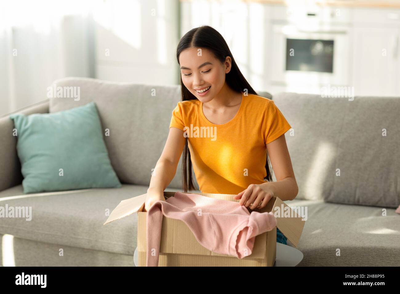 Delivery service. Positive asian lady unpacking parcel box with ...