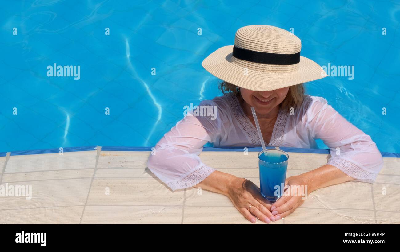 Senior woman relaxing in the hotel swimming pool. People are enjoying ...