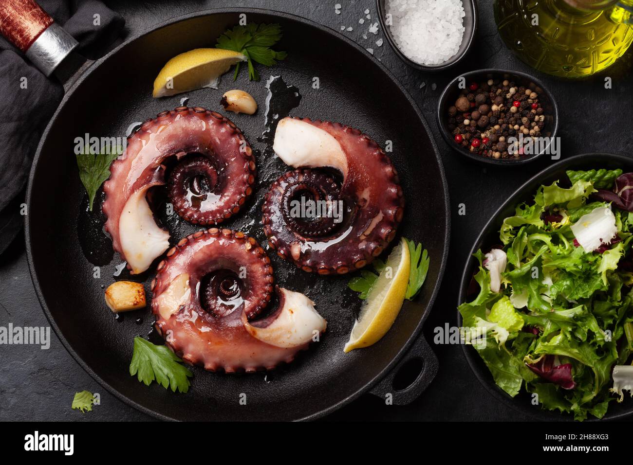 Grilled octopus with herbs and spices on frying pan. Top view flat lay ...