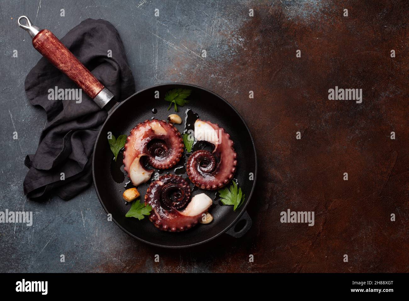 Grilled octopus with herbs and spices on frying pan. Top view flat lay ...