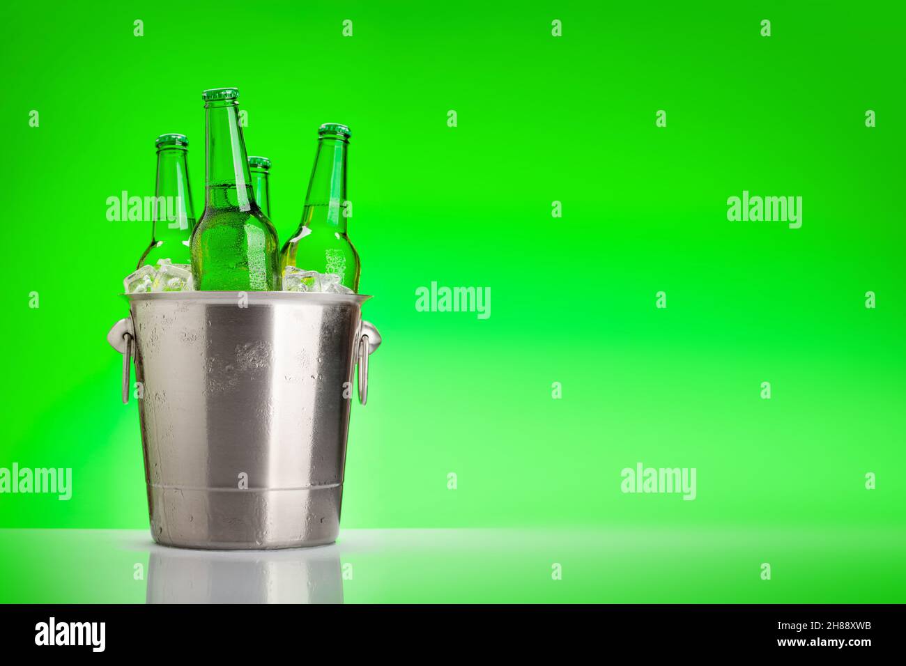 Beer bottles in ice bucket. Over green background Stock Photo - Alamy
