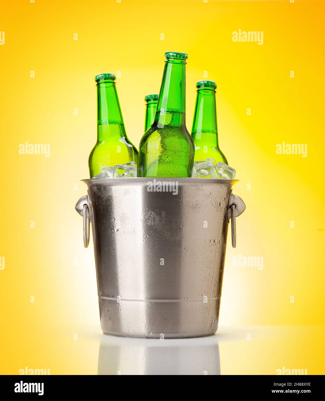 Beer bottles in ice bucket. Over yellow background Stock Photo - Alamy