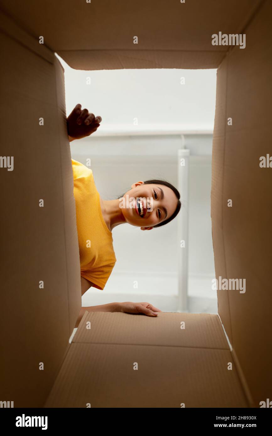Excited asian lady looking inside parcel box and smiling, getting ...