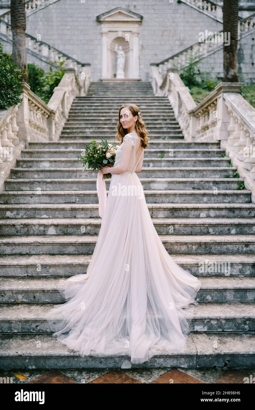 Bride in a long dress stands half-wrapped on stone steps Stock Photo ...