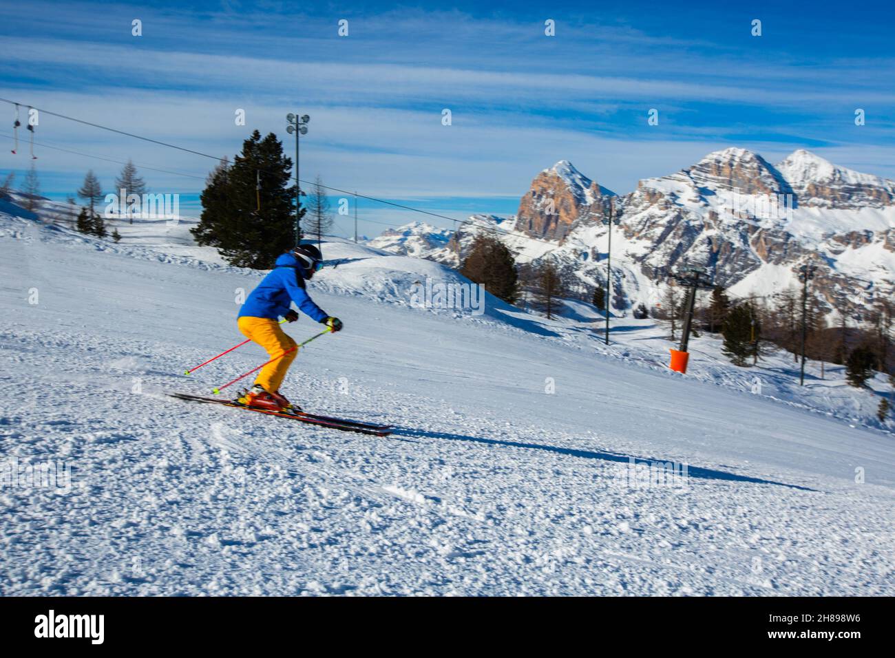 Male skier in blue and yellow clothes on slope with mountains in the ...