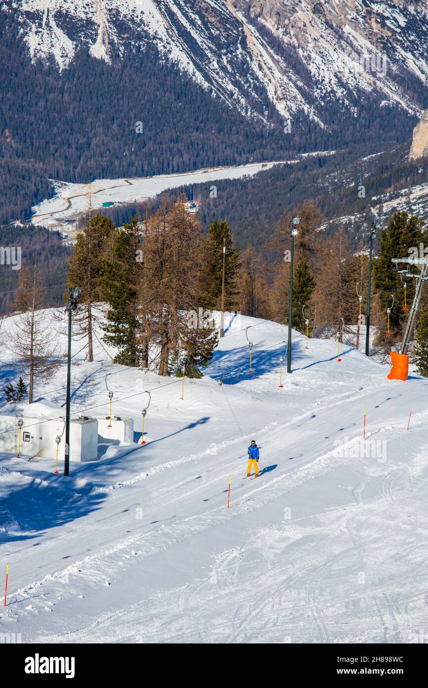 Male skier in blue and yellow clothes on slope with mountains in the ...