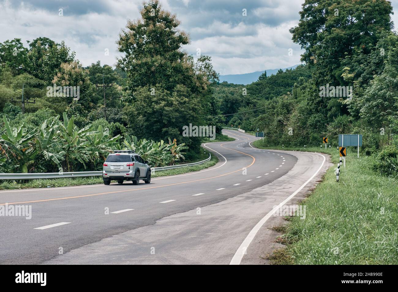 Car driving on winding road on top of mountain in tropical rainforest ...