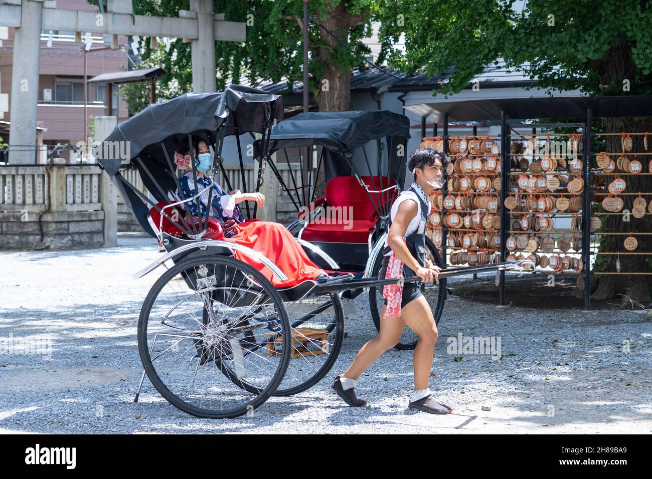 A young man pulls a traditional rickshaw carrying a Japanese women ...