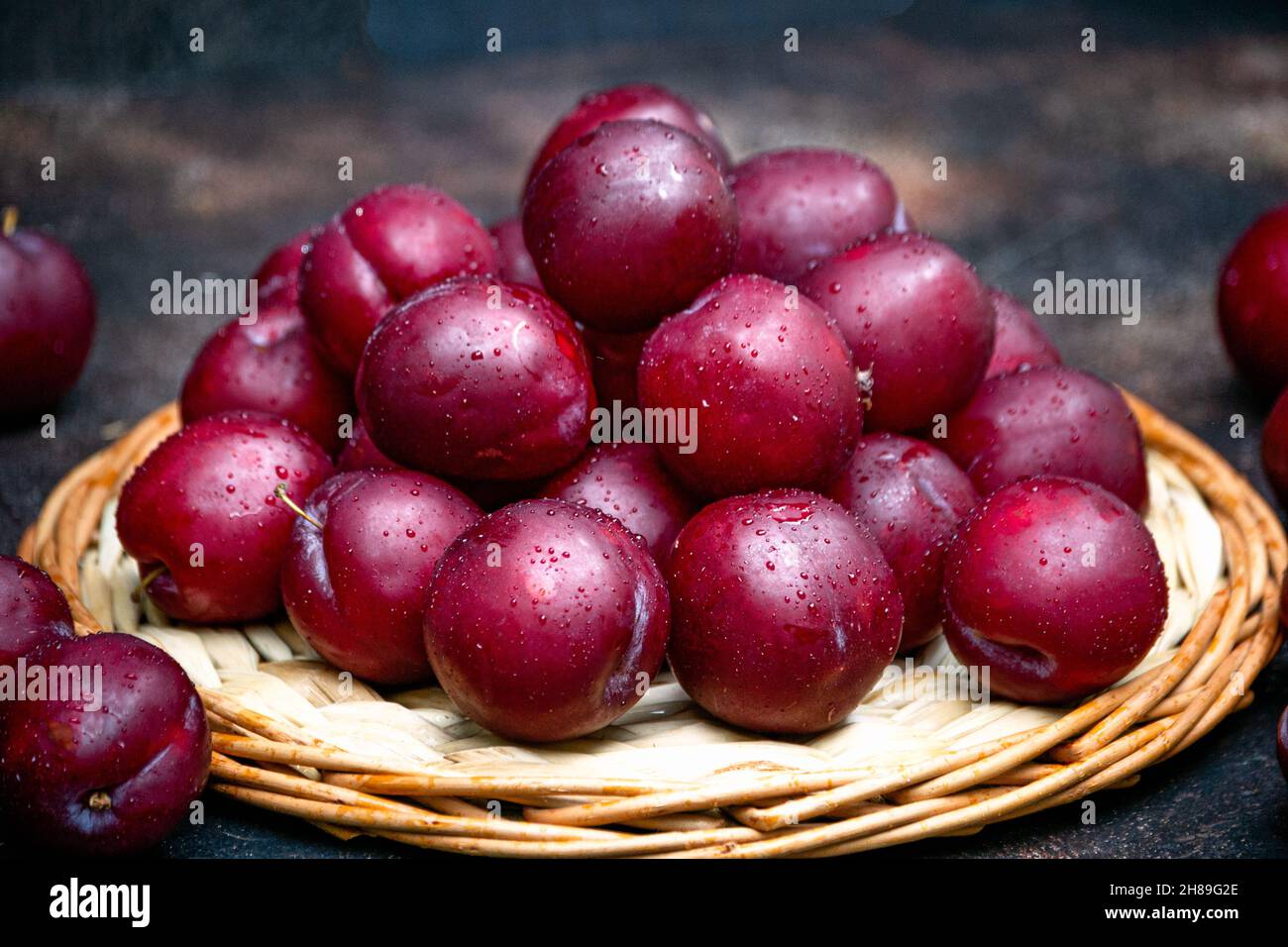 Fresh fruits of the ruby plum lie on a wicker tray Stock Photo - Alamy