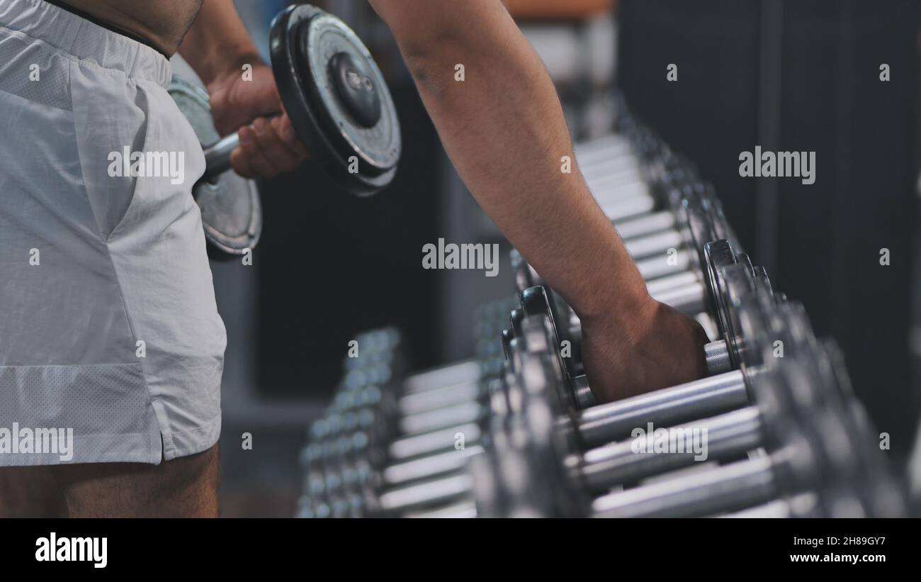 Arab man athlete is grabbing a dumbbell from a big selection in a ...