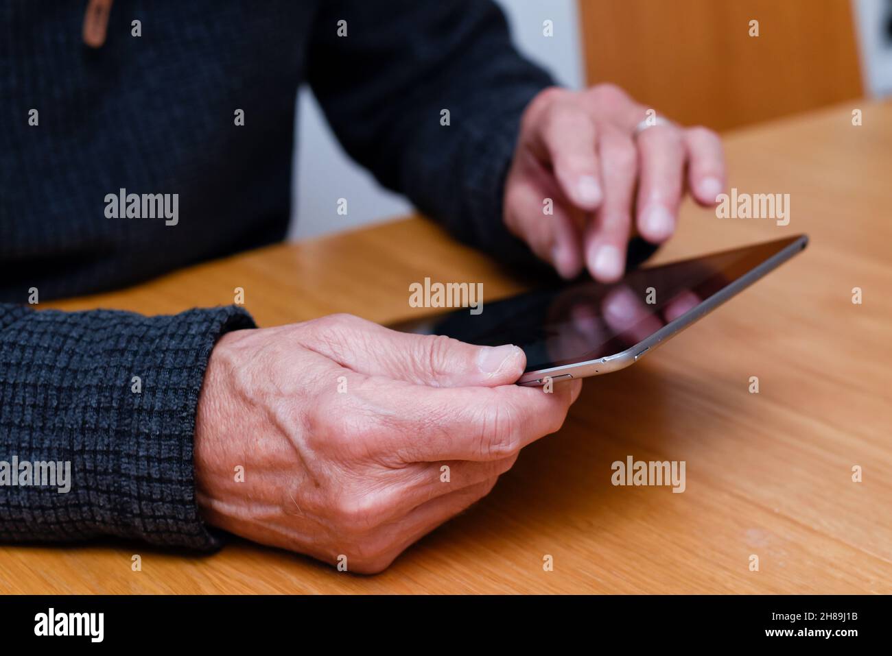 Mature hands hold a touch screen tablet device to stay connect online ...