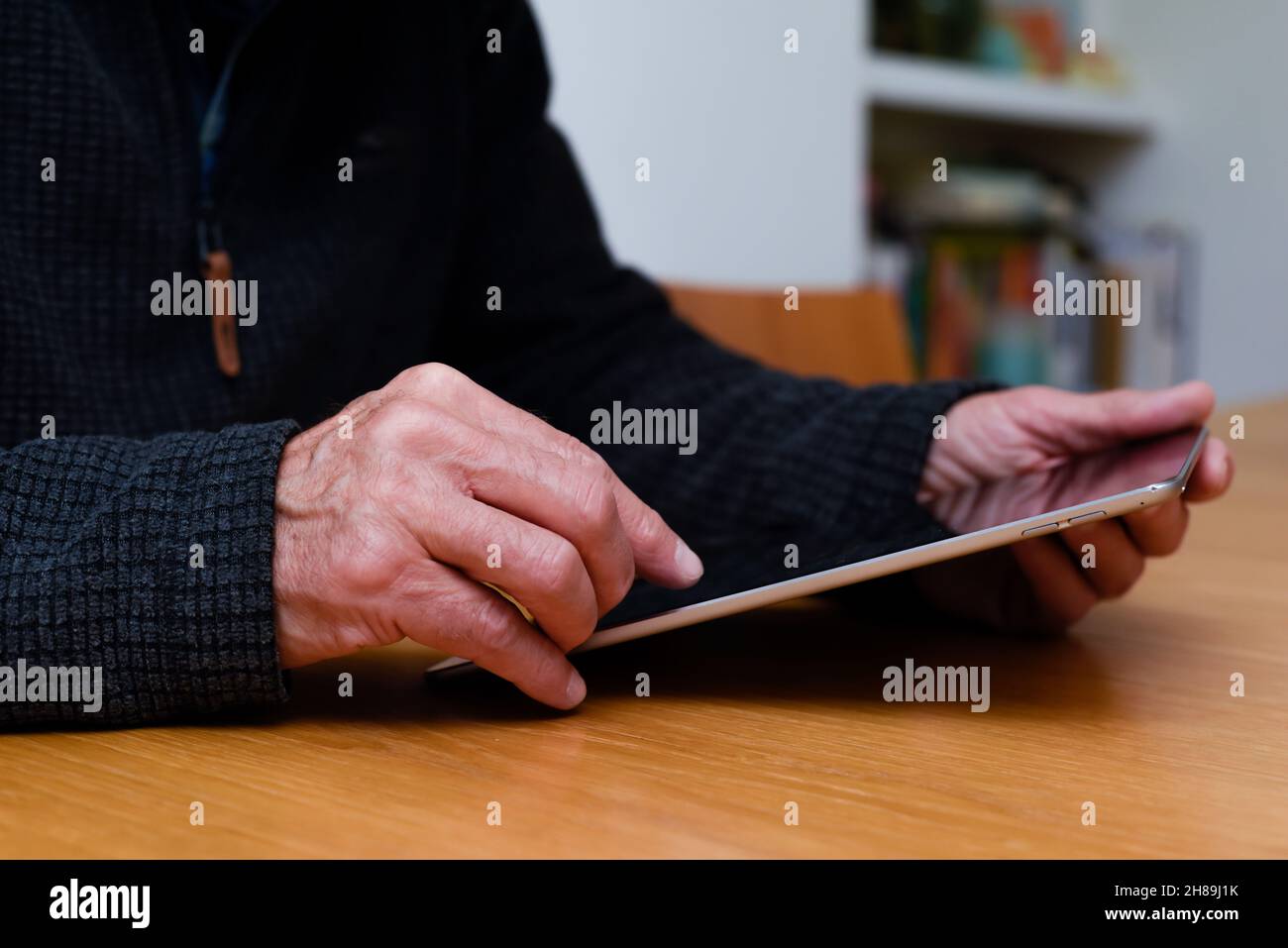 Mature hands hold a touch screen tablet device to stay connect online ...