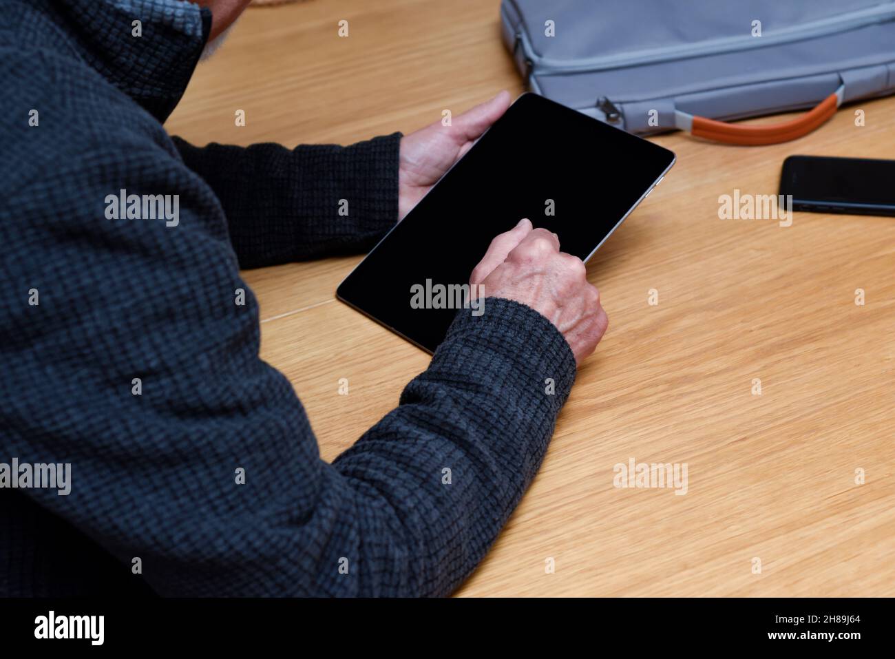 Mature hands hold a touch screen tablet device to stay connect online ...