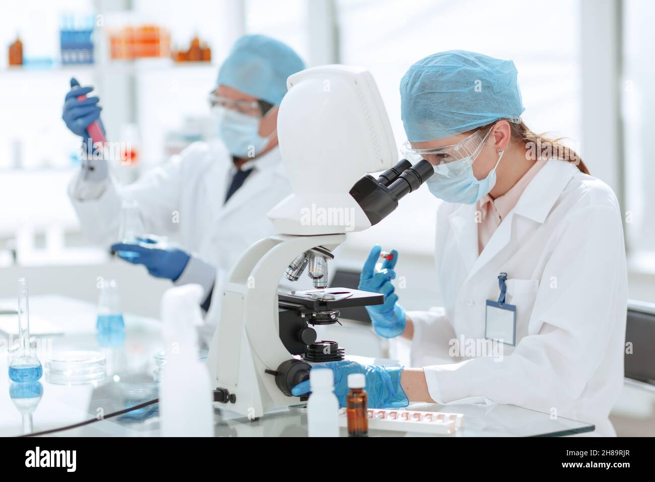 female scientist sitting in front of a microscope Stock Photo - Alamy