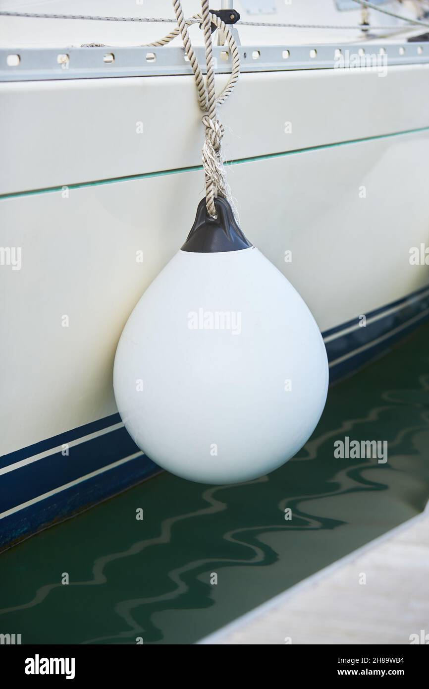 White fenders suspended between a boat and dockside for protection ...