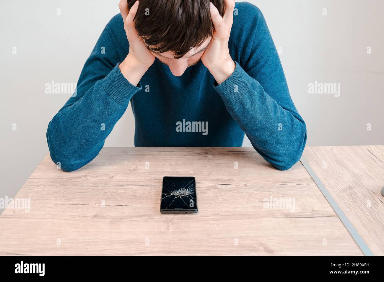 frustrated young man looking at a smartphone with a broken screen Stock ...