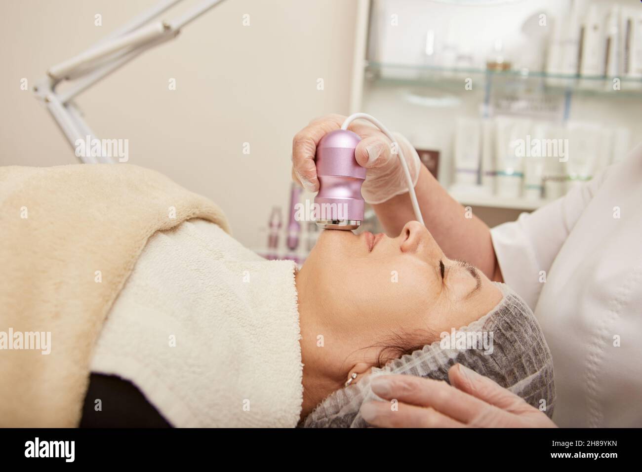 Beautician hand massaging woman chin with cryotherapy massager Stock ...
