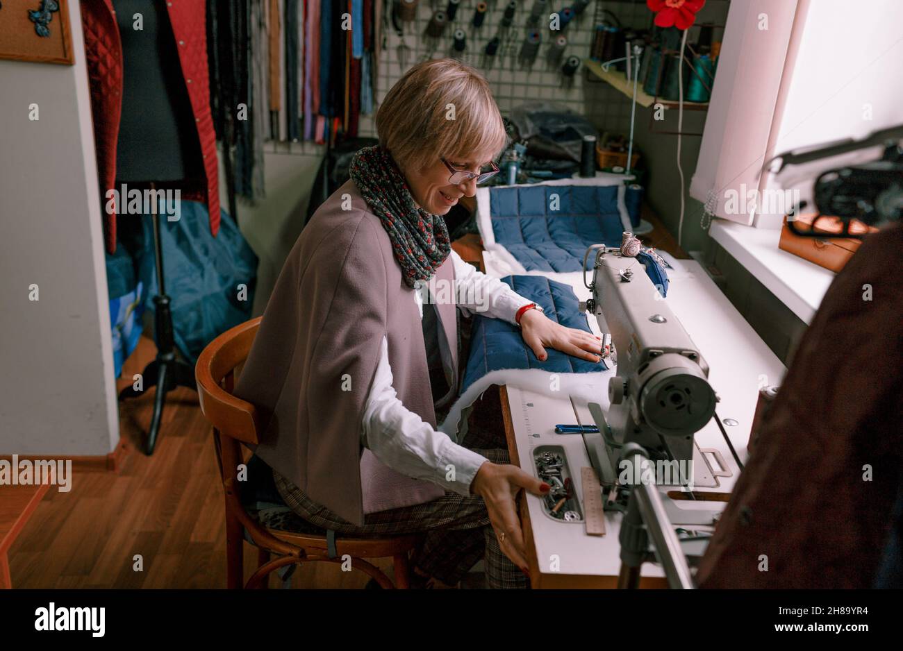 A female dressmaker uses a sewing machine to create custom-made clothes ...