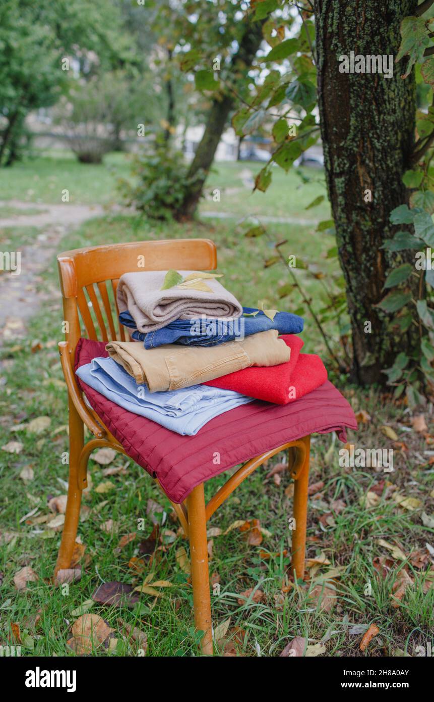 an antique chair with clothes stacked on the street. textiles clothing ...