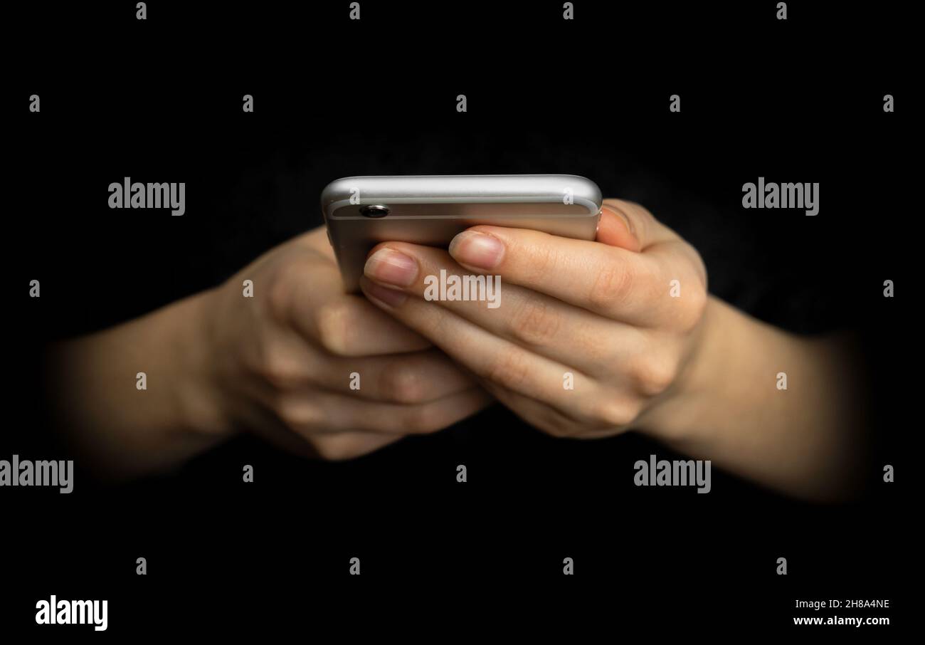 Businesswoman uses mobile phone, front view. Black background, hands ...