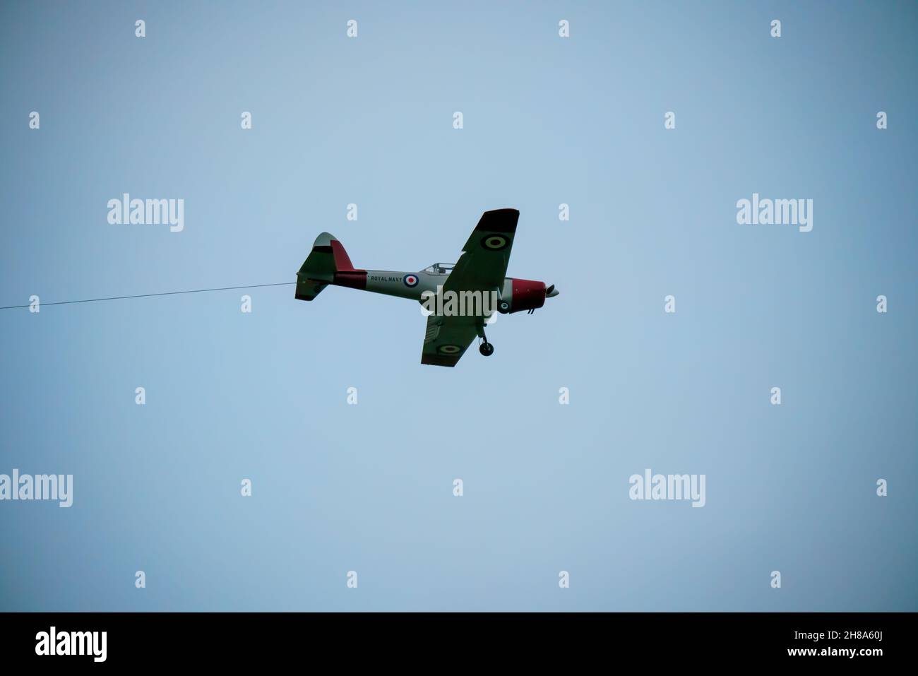 a 1950s De Havilland DHC-1 Chipmunk flies low overhead in a winter sky ...